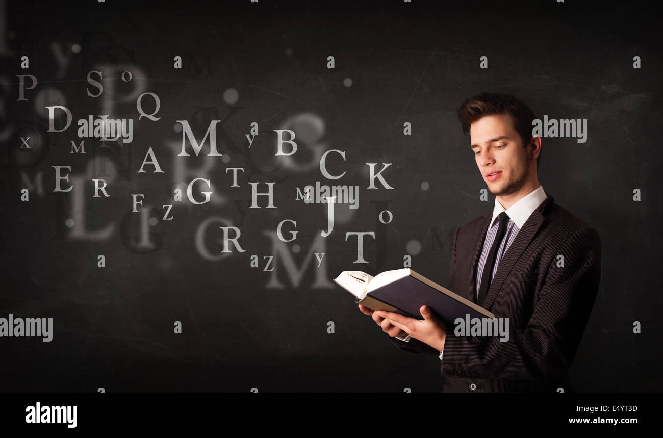 Young man reading a book with alphabet letters Stock Photo - Alamy