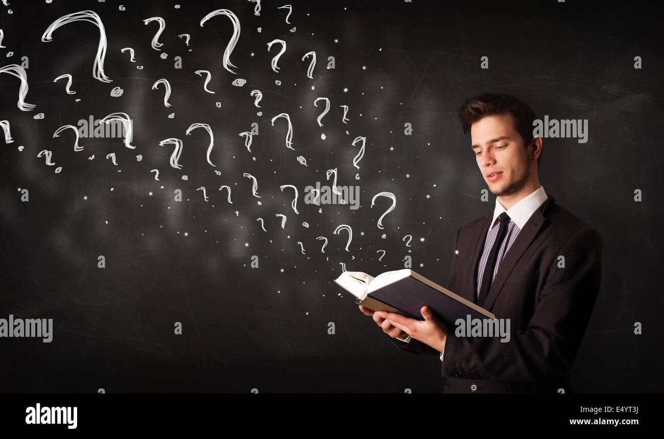 Young man reading a book with question marks coming out from it Stock ...