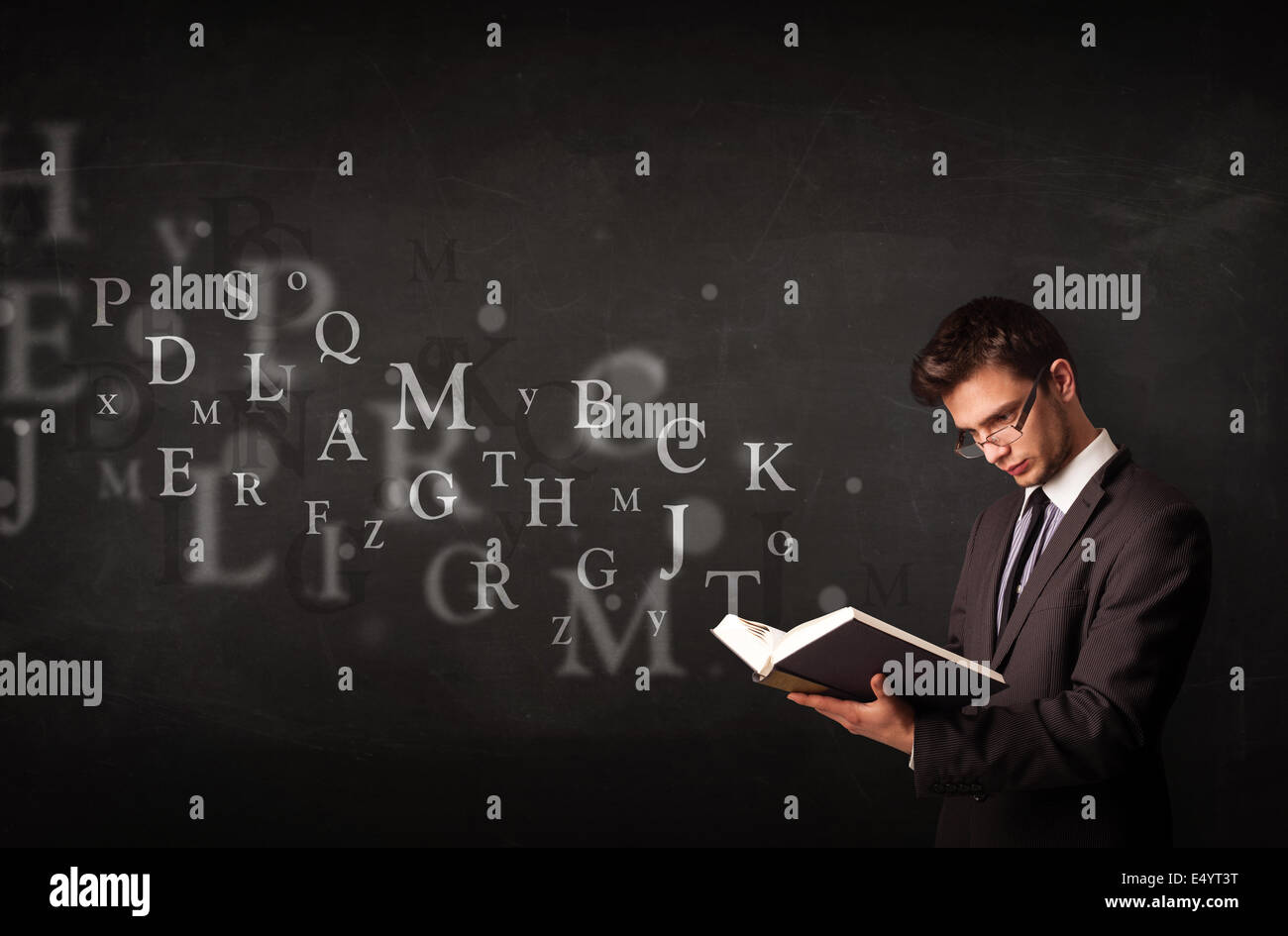 Young man reading a book with alphabet letters Stock Photo - Alamy