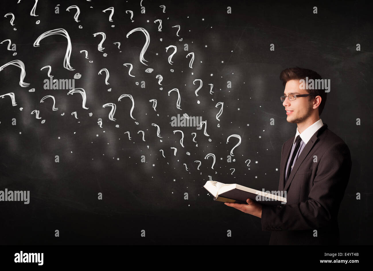 Young man reading a book with question marks coming out from it Stock ...