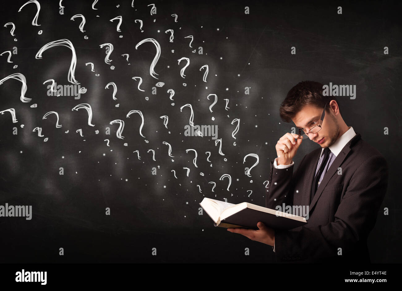 Young man reading a book with question marks coming out from it Stock ...
