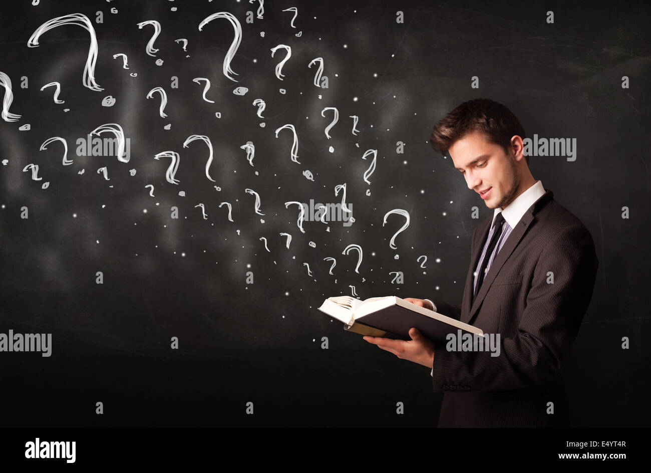 Young man reading a book with question marks coming out from it Stock ...