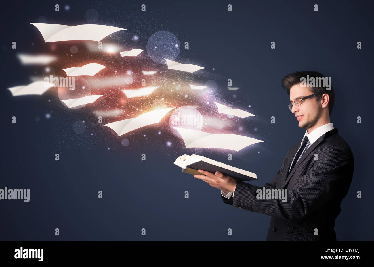 Young guy reading a book with flying sheets coming out of the book ...