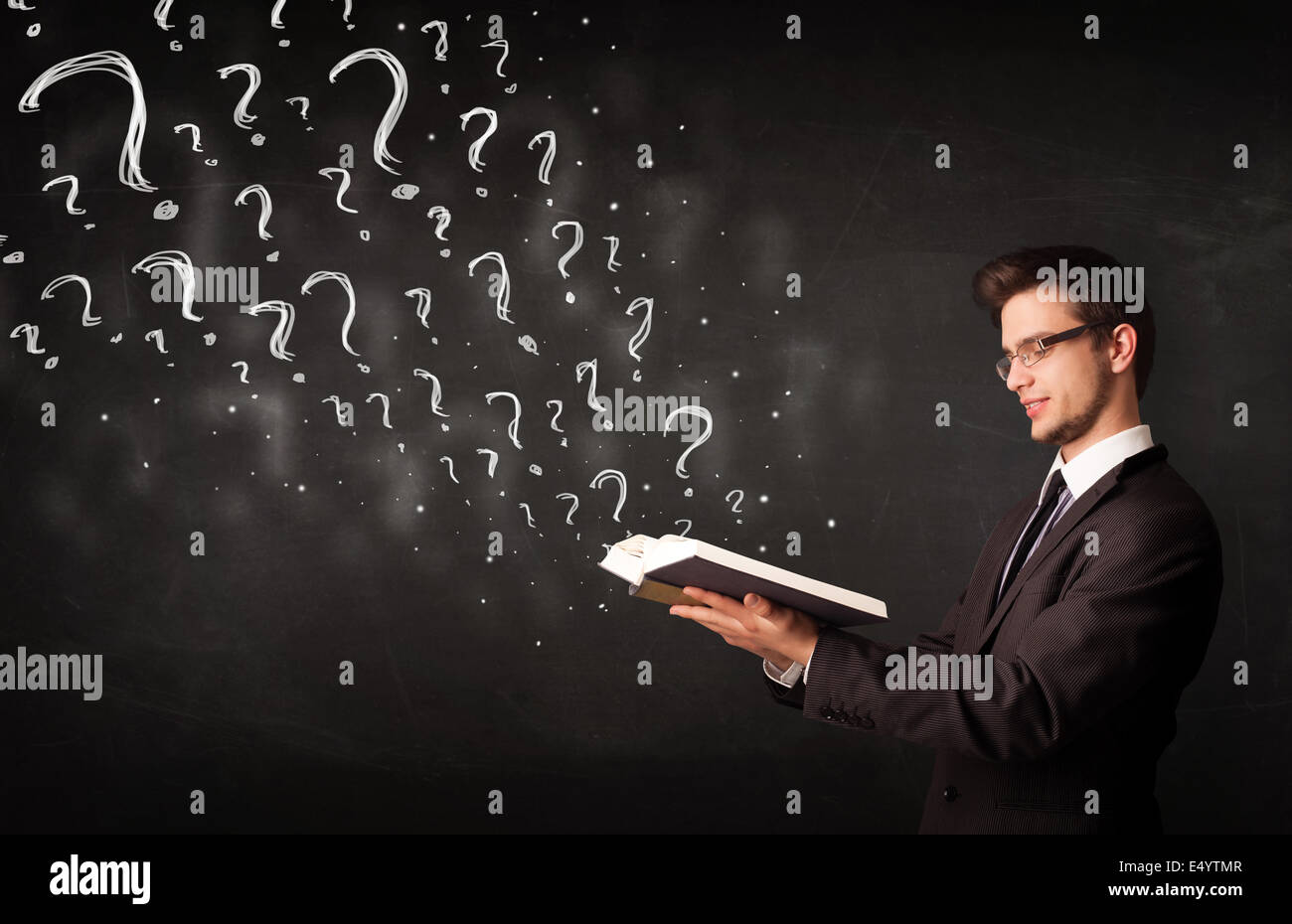 Young man reading a book with question marks coming out from it Stock ...