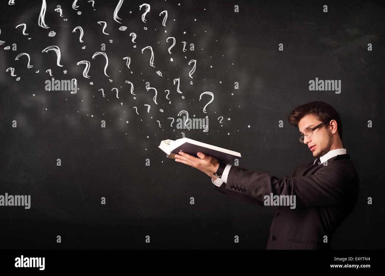 Young man reading a book with question marks coming out from it Stock ...
