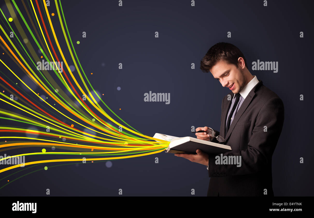 Handsome man reading a book while colorful lines are coming out of the ...