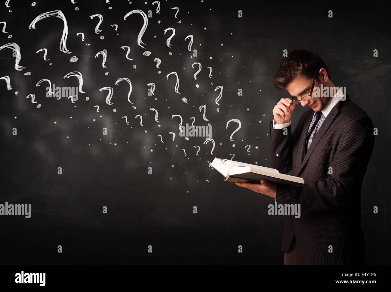 Young man reading a book with question marks coming out from it Stock ...