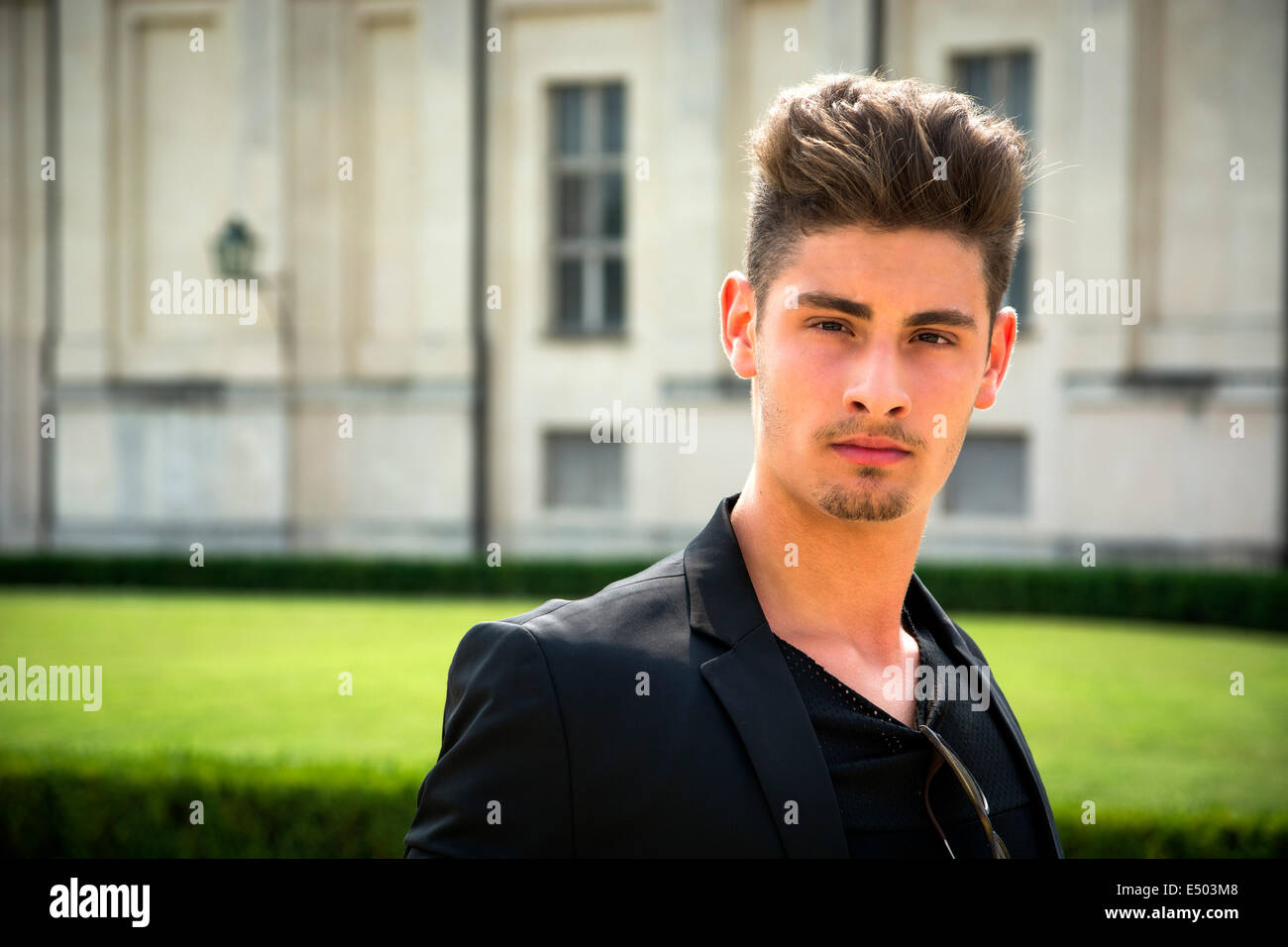 Handsome young man outdoors, old elegant royal palace behind him ...