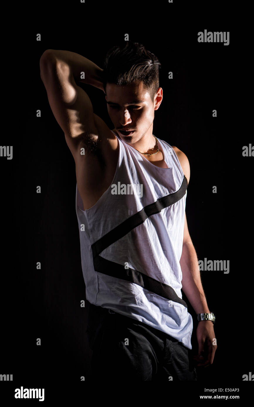 Portrait of handsome young man in white tank-top isolated on black ...