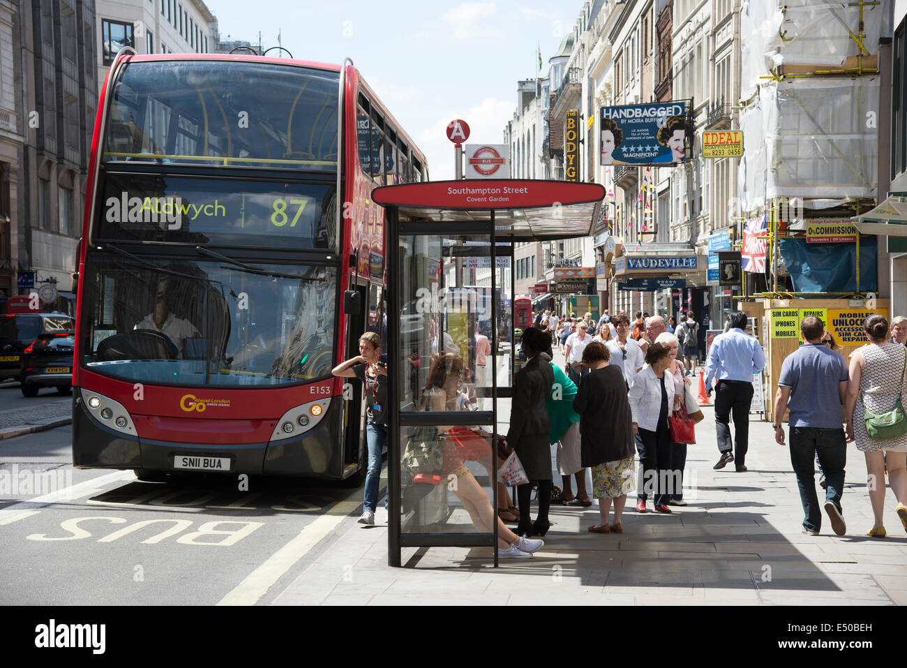 The Strand London UK busy with visitors Red bus at bus stop number 87 ...