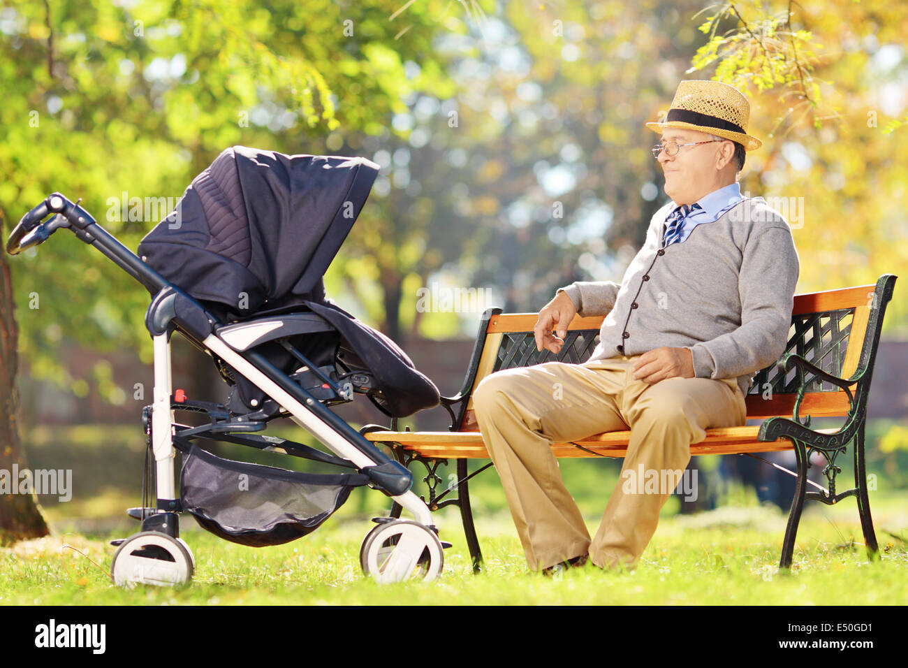 Grandfather sitting and looking at his baby nephew in a stroller, in a ...