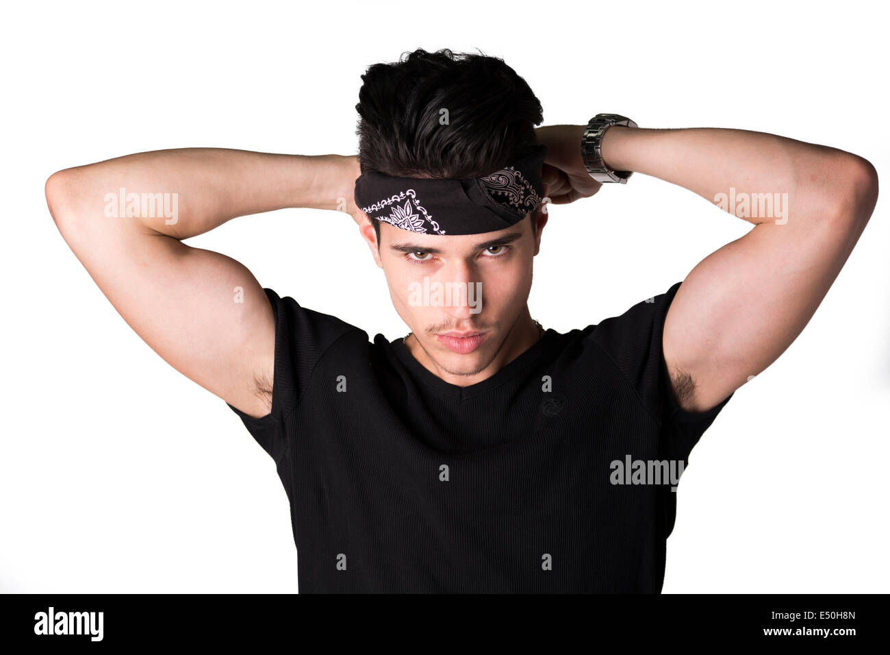 Handsome young man tying headband around his head looking at camera ...