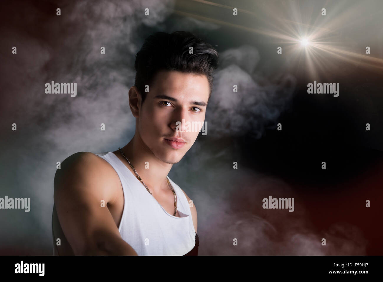 Handsome young man posing looking down at the camera with a serious ...