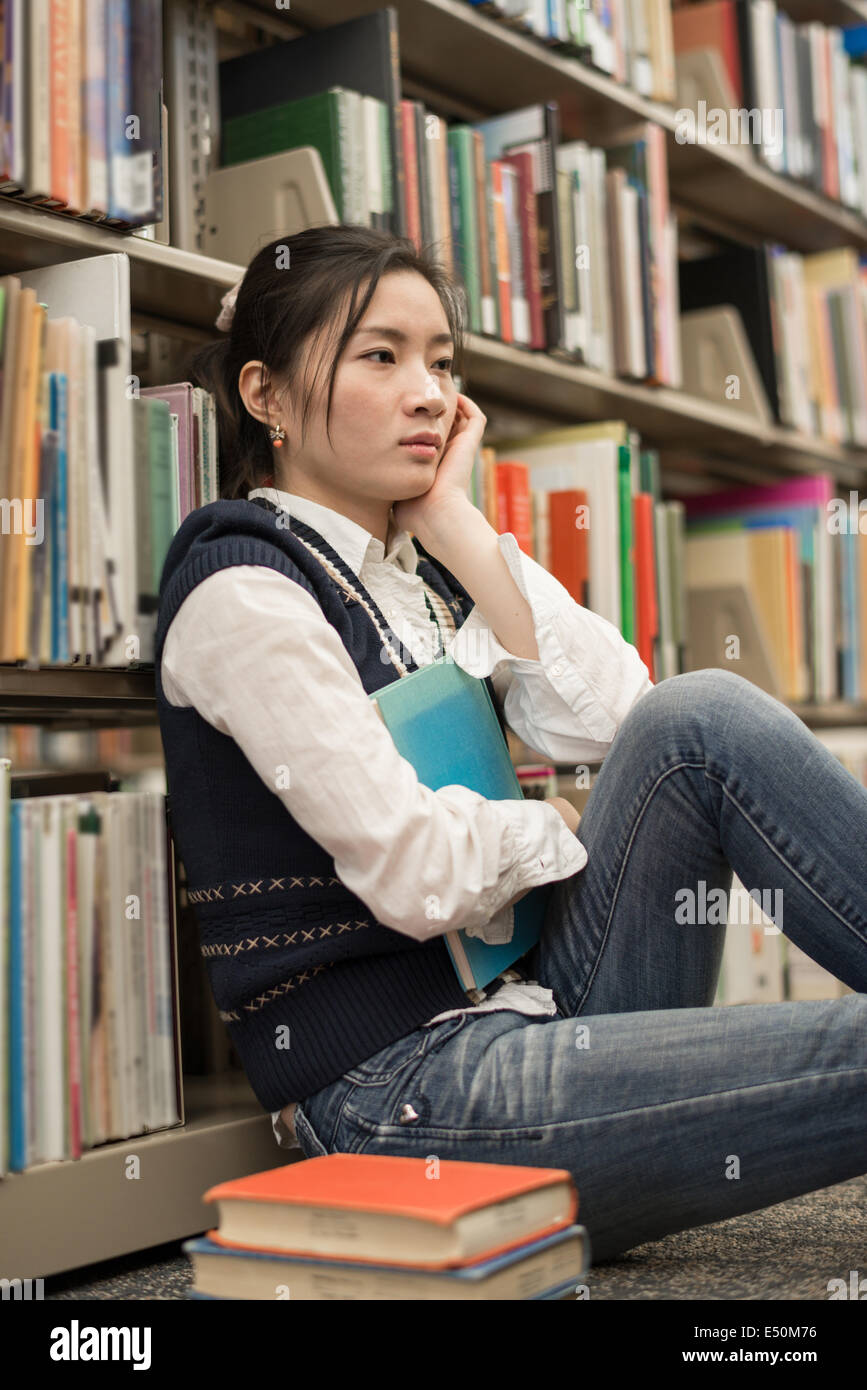 Student next to bookshelf looking depressed Stock Photo - Alamy