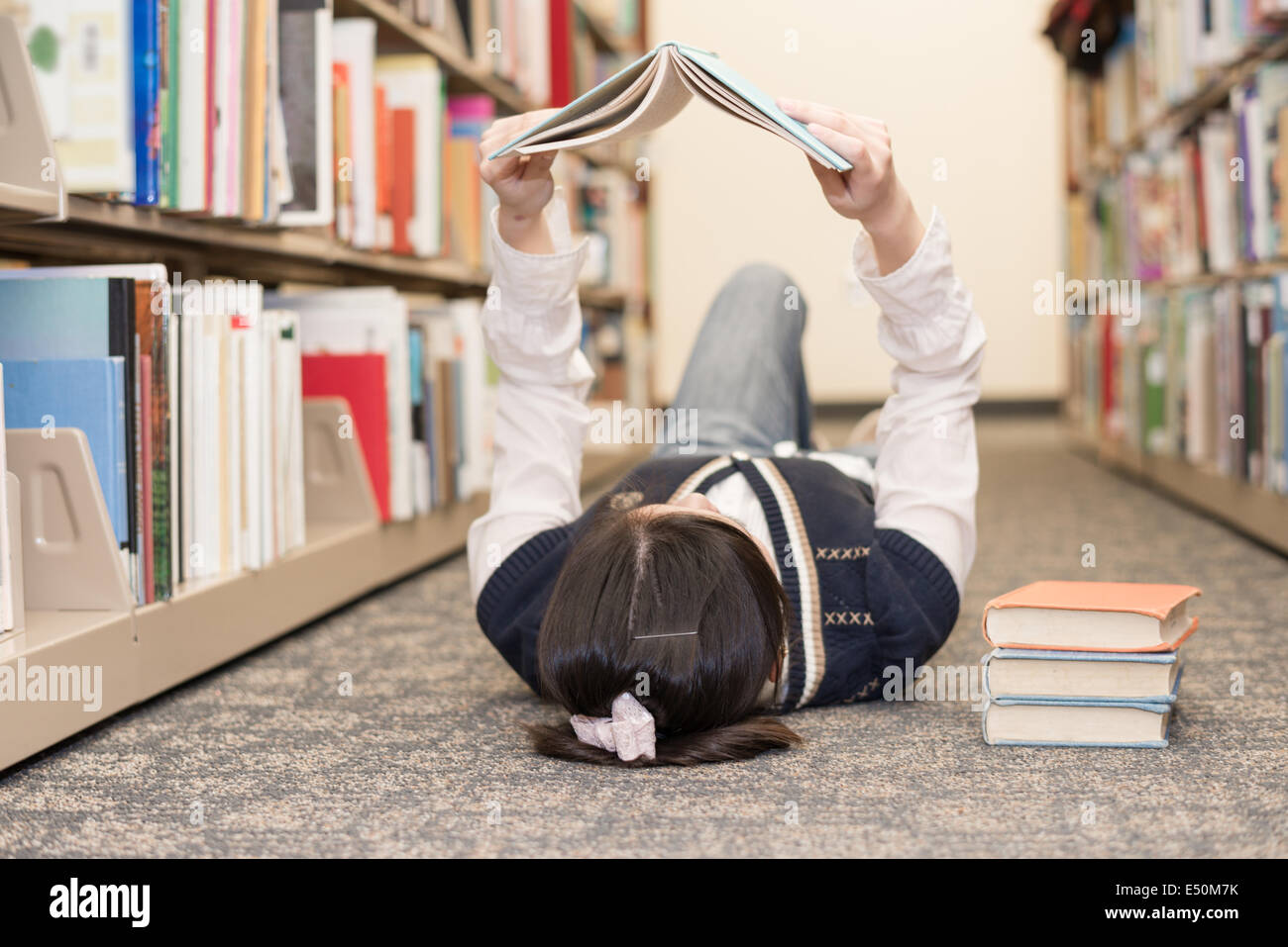Student laying on floor reading book Stock Photo - Alamy