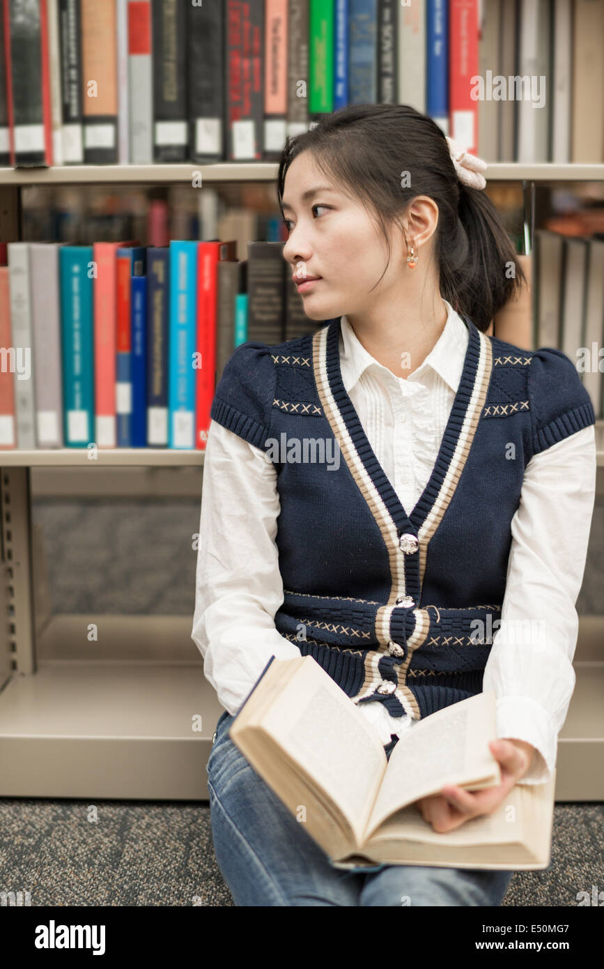 Student sitting on the floor holding book Stock Photo - Alamy
