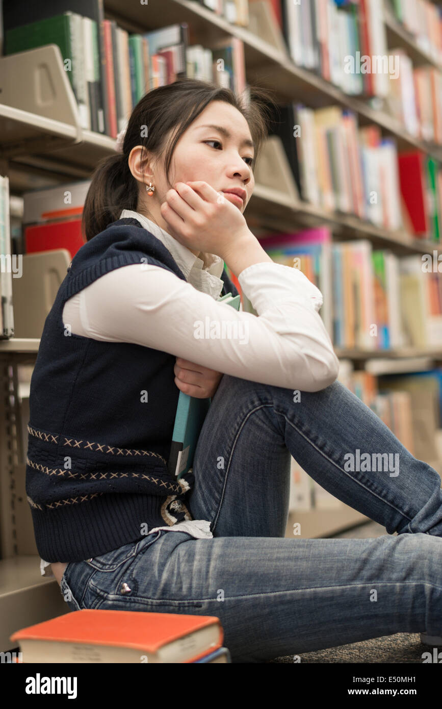 Student next to bookshelf looking depressed Stock Photo - Alamy