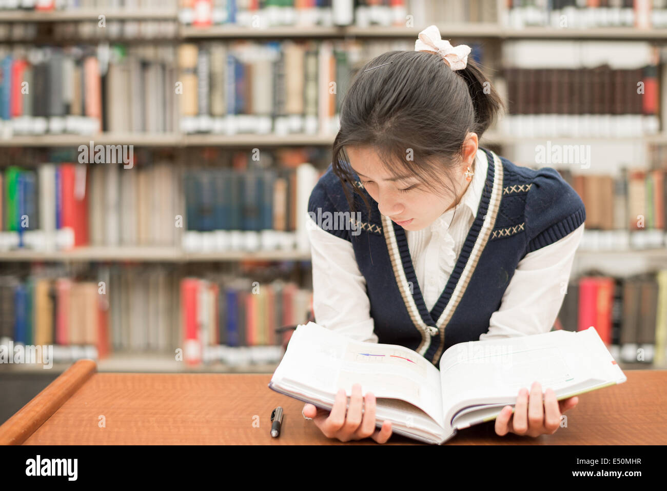 Student reading a textbook in library Stock Photo - Alamy