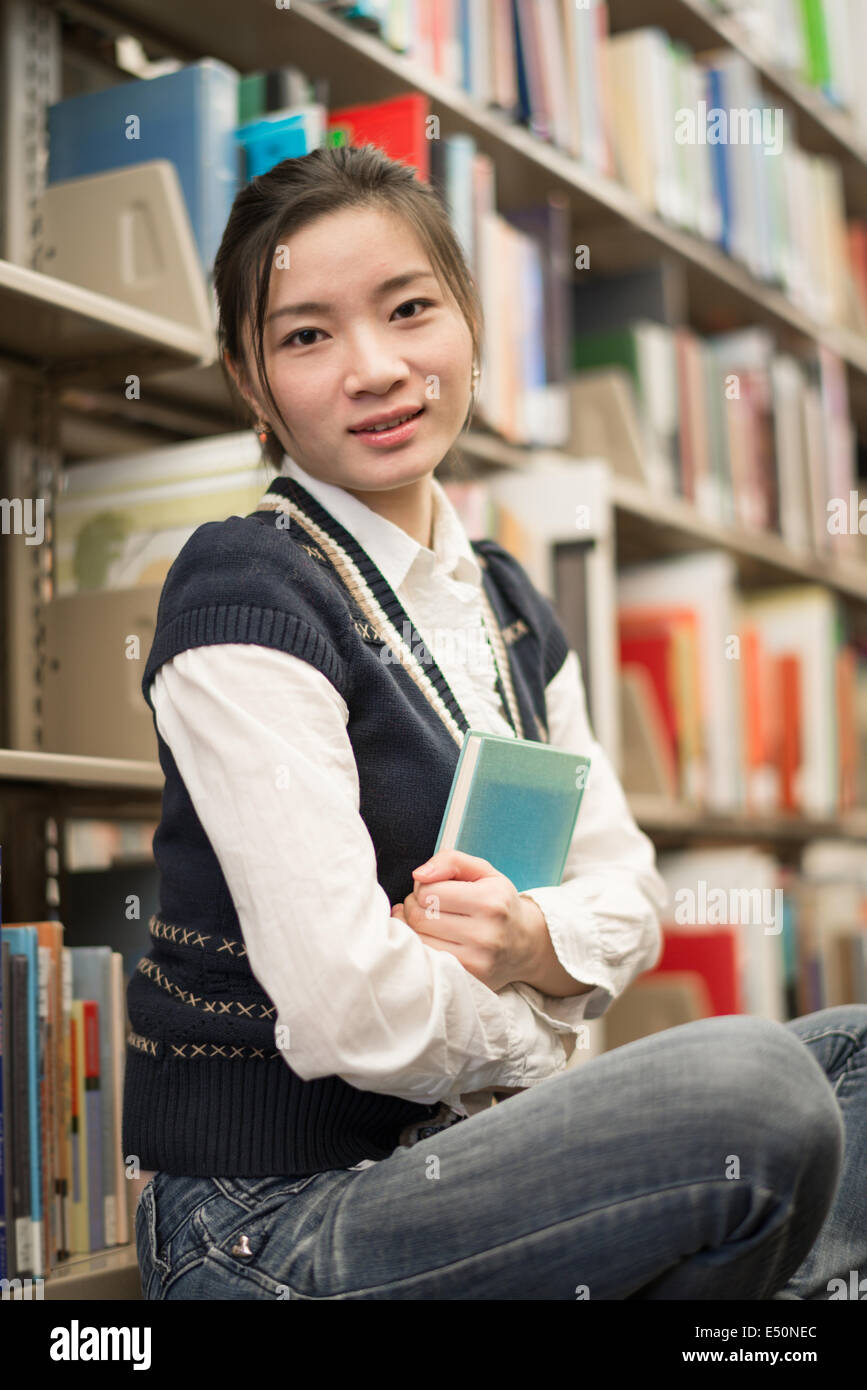 Girl huggering a book near bookshelf Stock Photo - Alamy