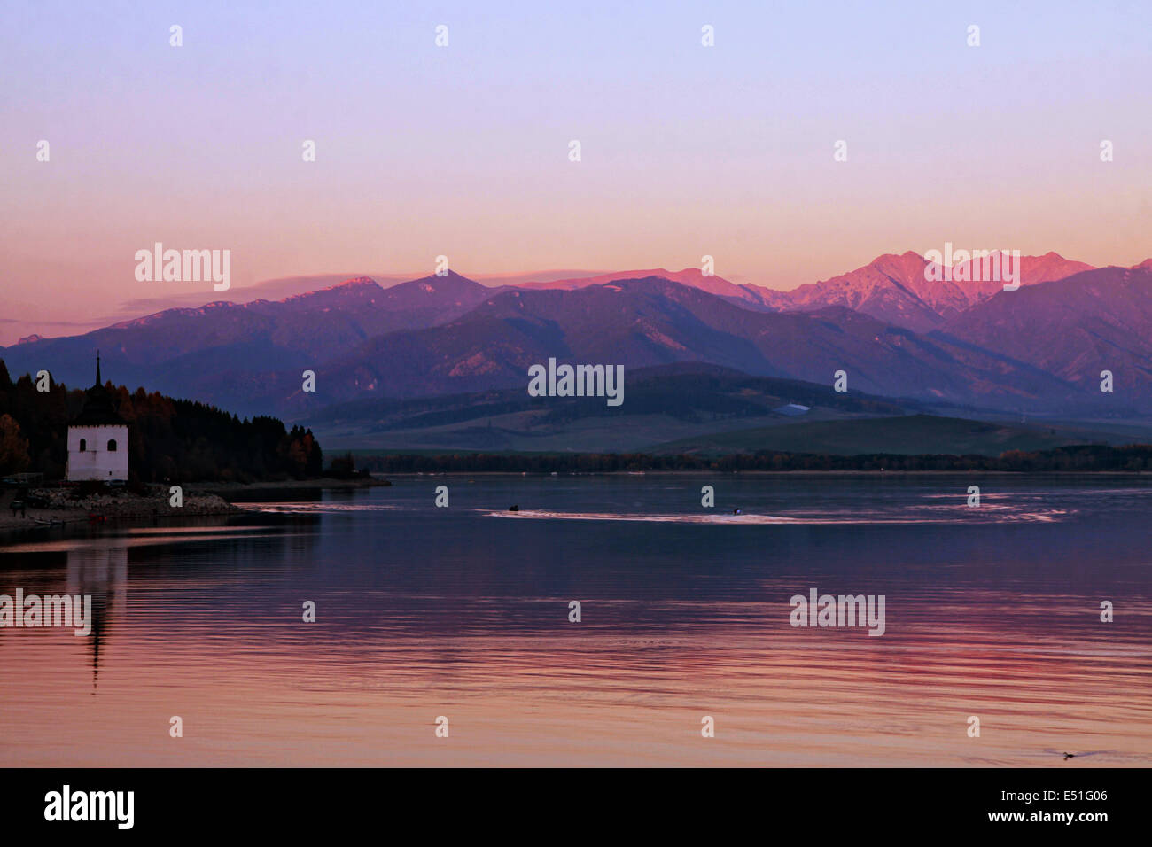 Lake with a chapel by sunset Stock Photo - Alamy