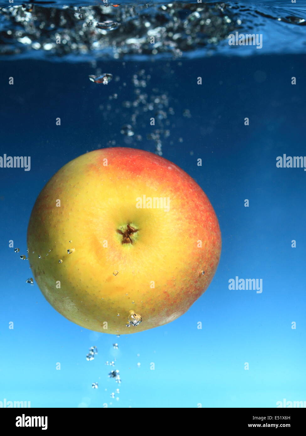 Yellow apple in the water splash over blue Stock Photo - Alamy