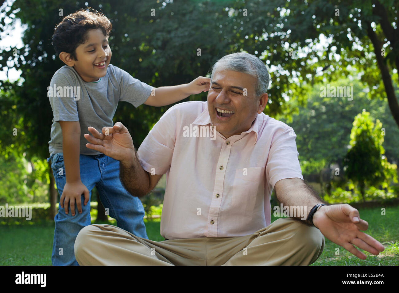 Grandson tickling grandfather in ear Stock Photo - Alamy