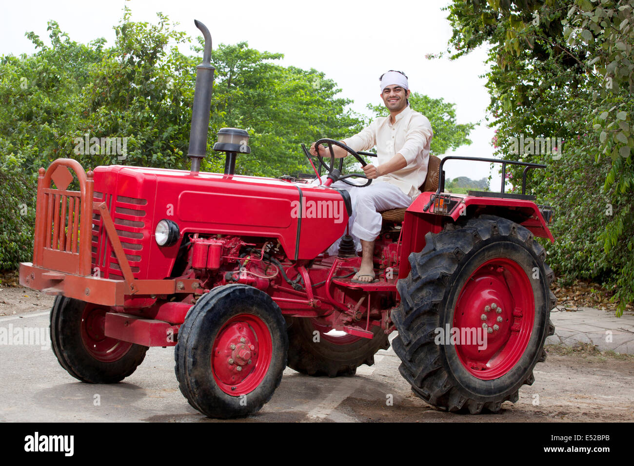 Portrait of a farmer sitting on a tractor smiling Stock Photo - Alamy