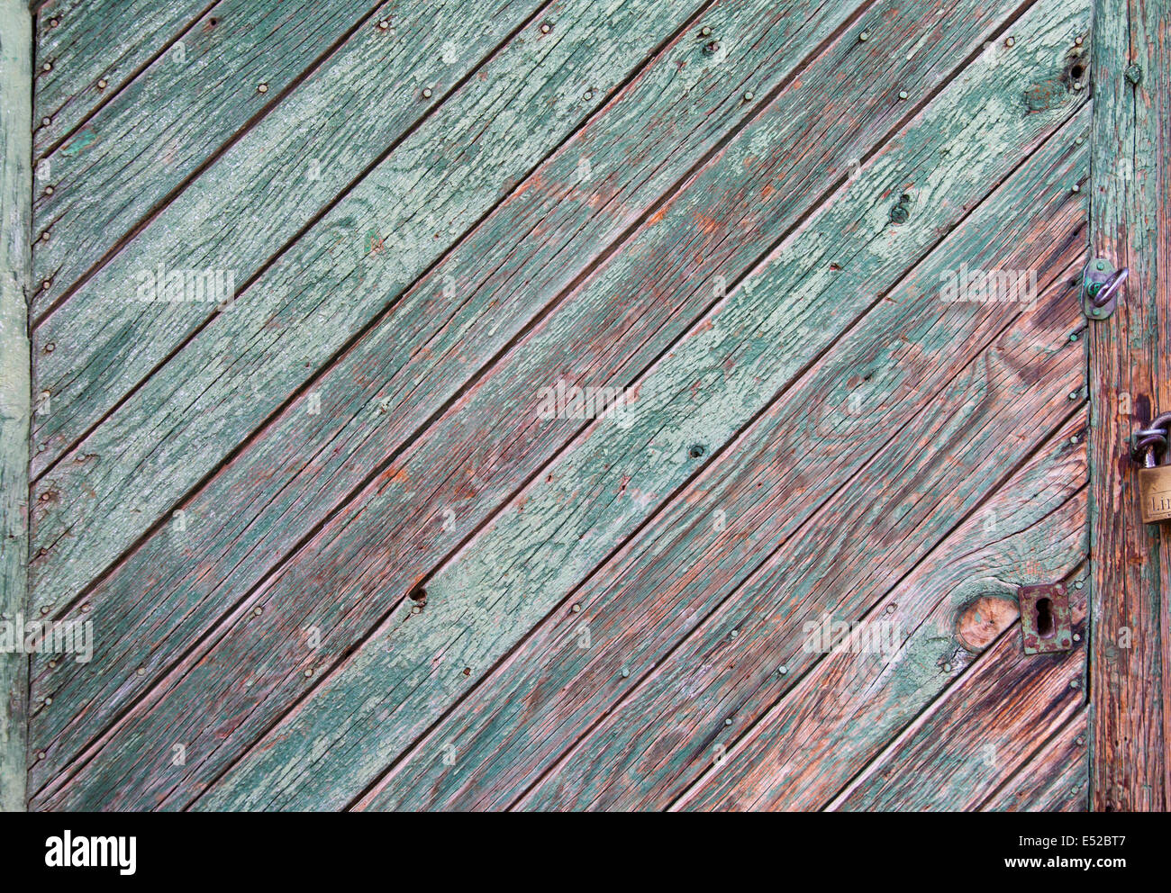 Green paint peeling from a wooden panel door showing the wood grain and ...