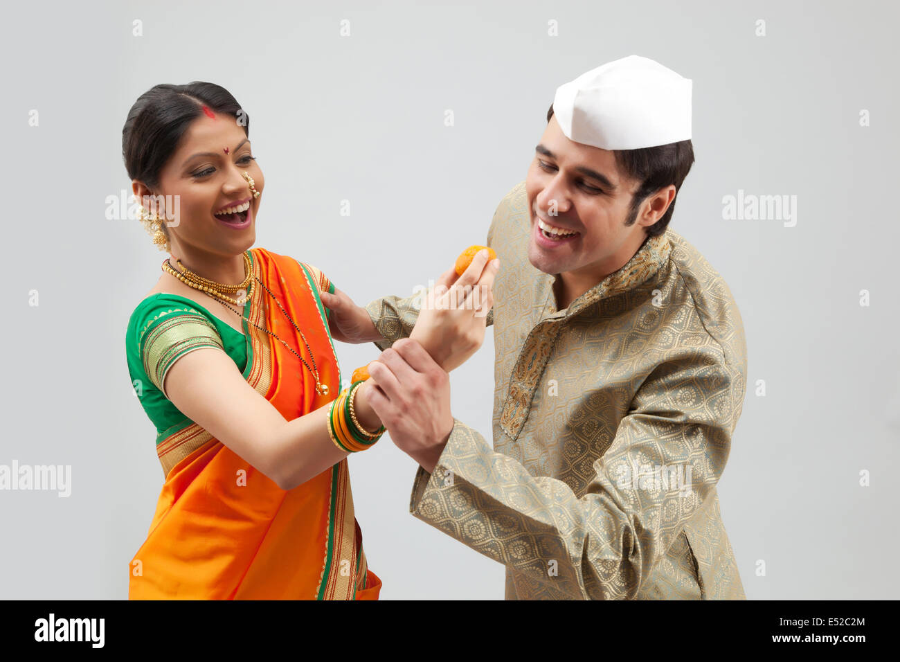 Maharashtrian man trying to eat a laddoo from a woman's hand Stock ...