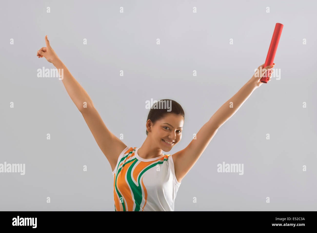 Portrait of female relay runner celebrating victory isolated over gray ...