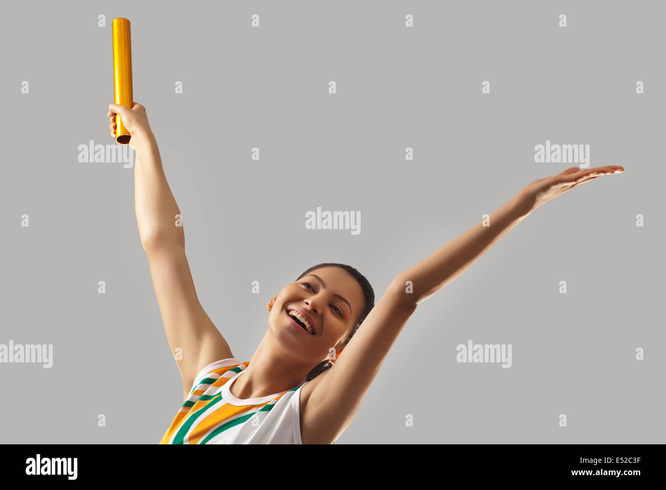 Young sports woman with relay baton celebrating victory isolated over ...
