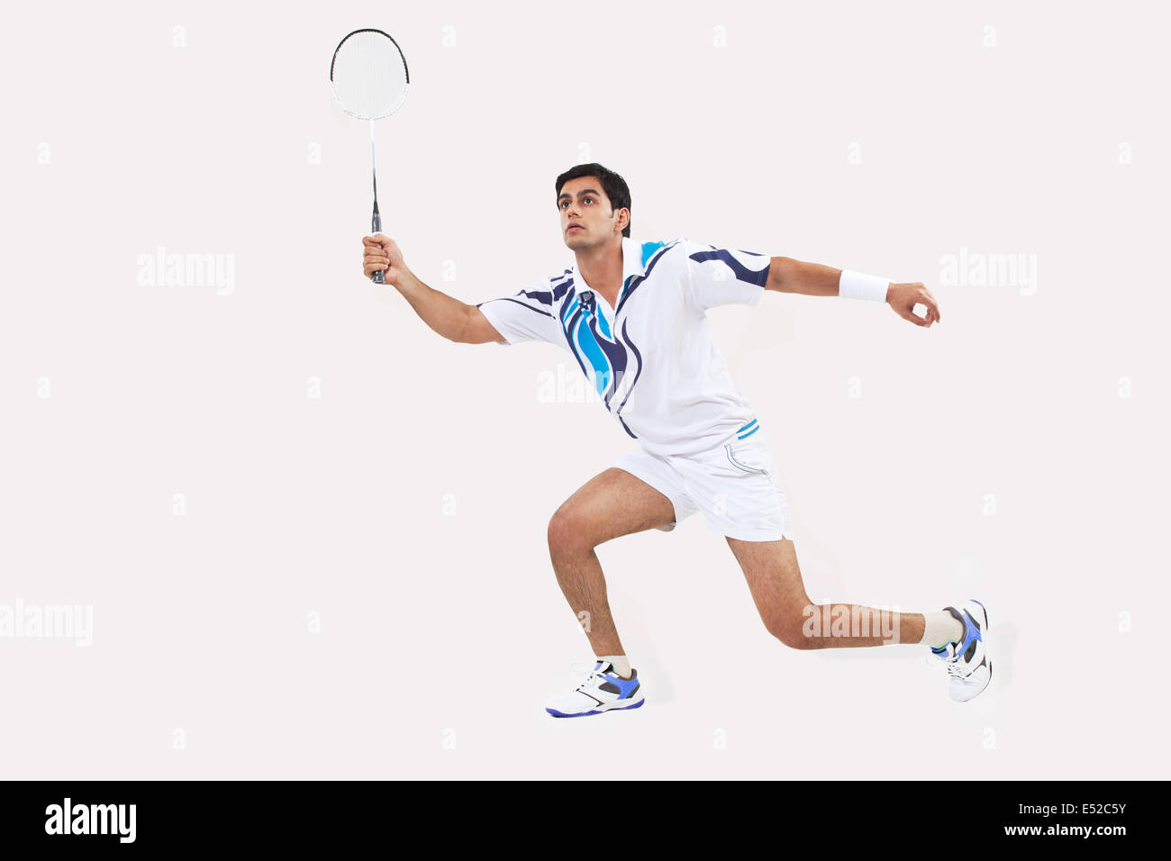 Young man in sports wear playing badminton against white background ...