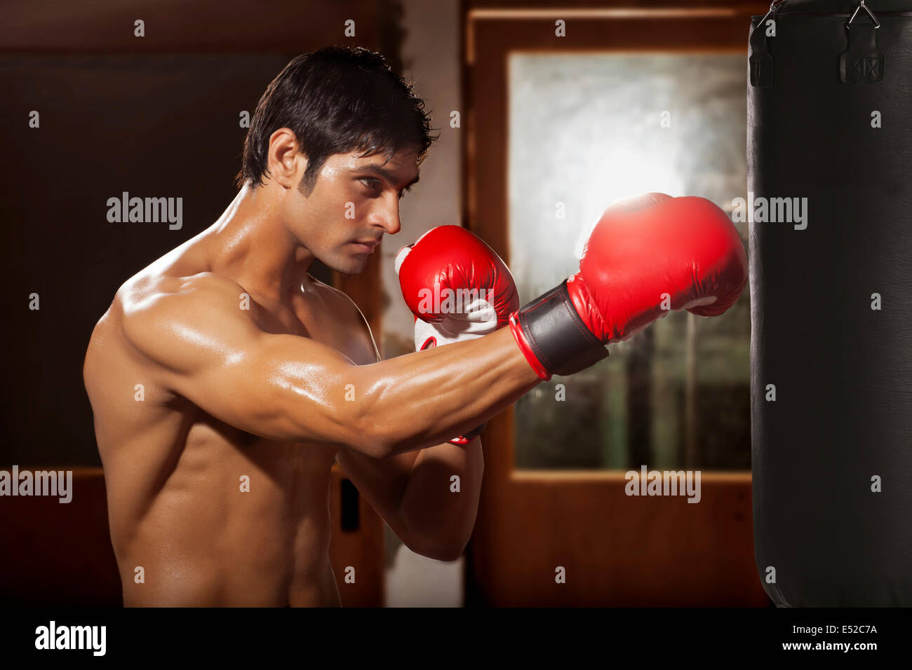 Young shirtless boxer working out with black punching bag in gym Stock ...