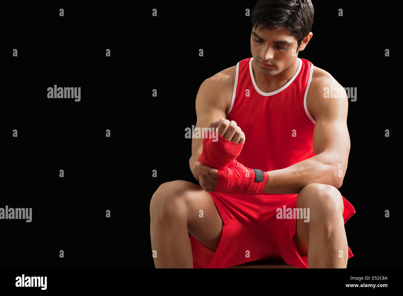 Young male boxer taping up hands against black background Stock Photo ...