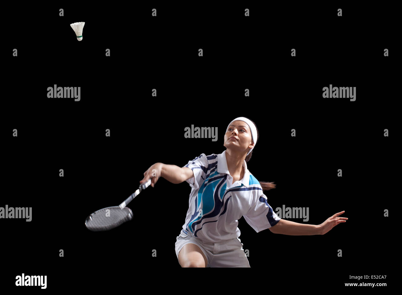 Woman hitting shuttlecock with badminton racket isolated over black ...