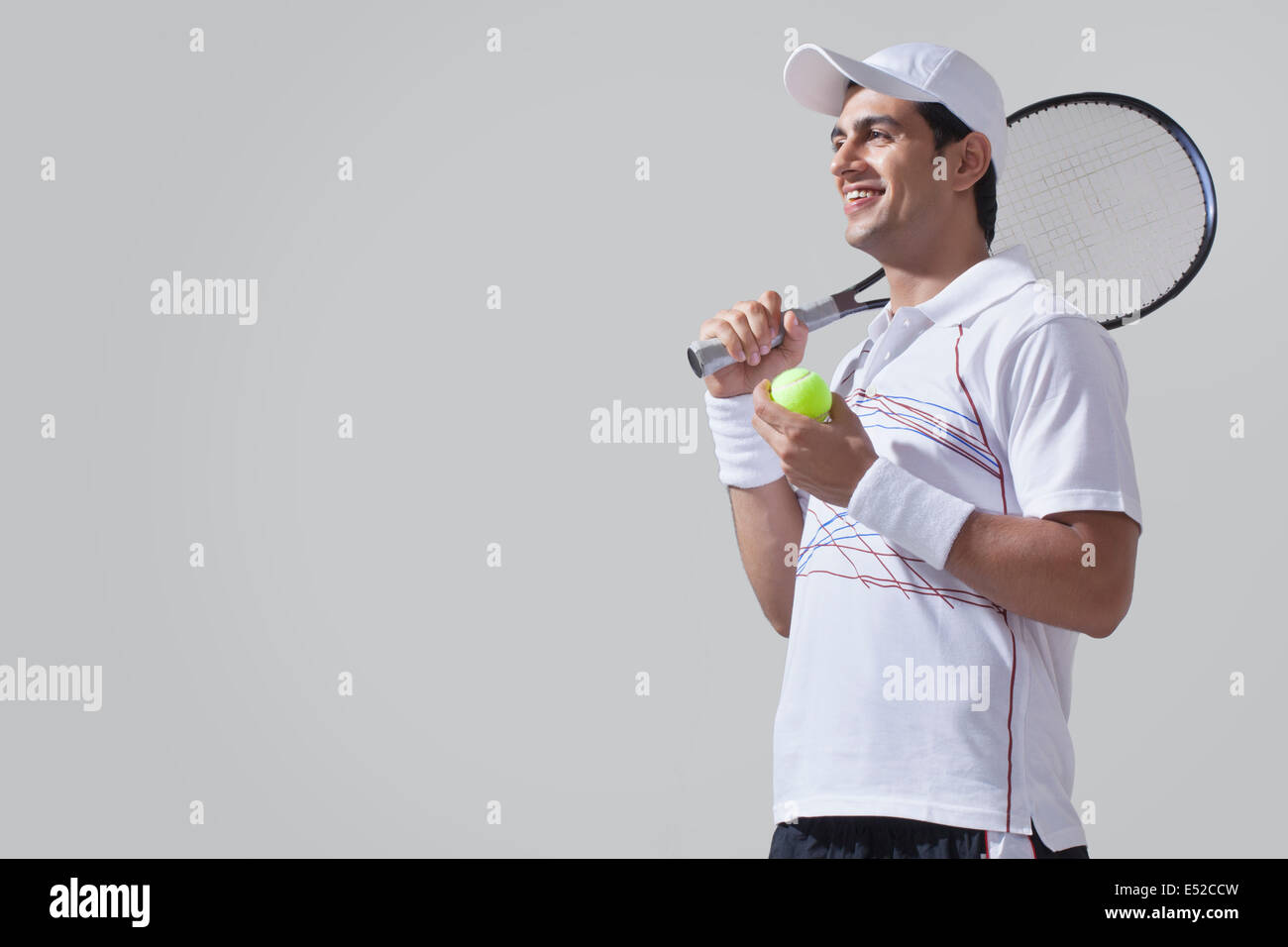 Low angle view of young man holding tennis racket and ball isolated ...