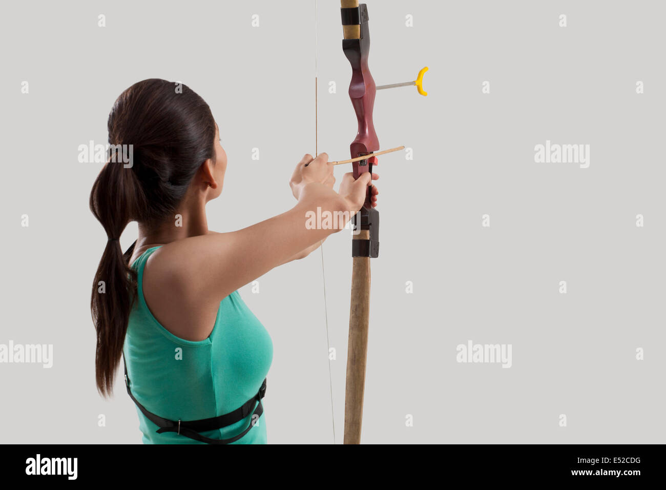 Female archer practicing archery against gray background Stock Photo ...