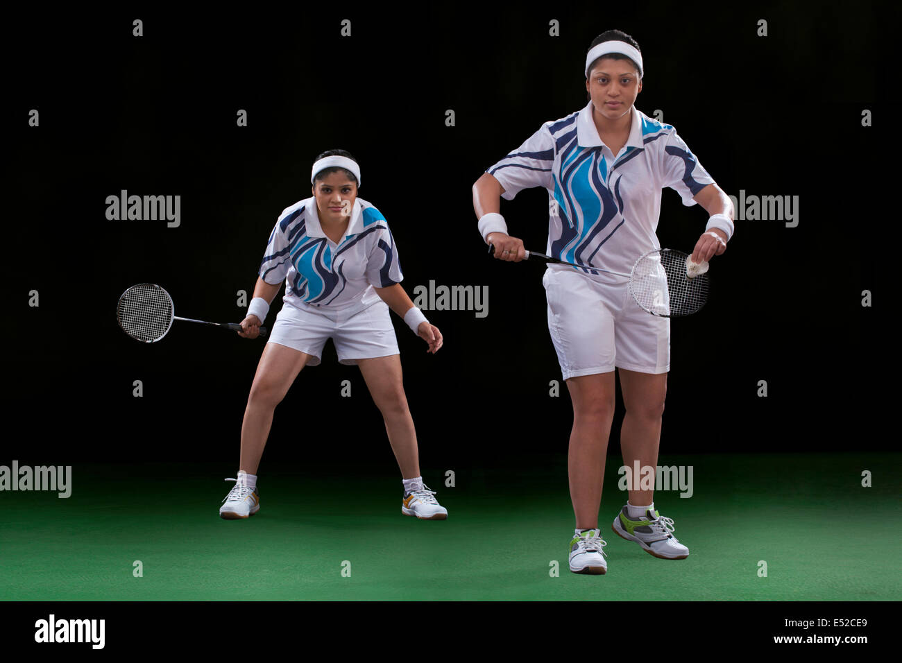 Portrait of young women playing badminton over black background Stock ...
