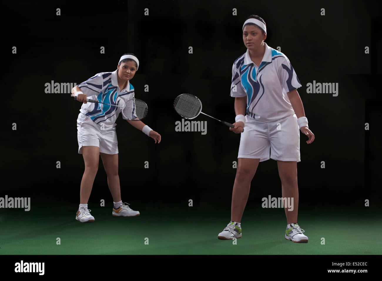 Young female partners playing badminton over black background Stock ...