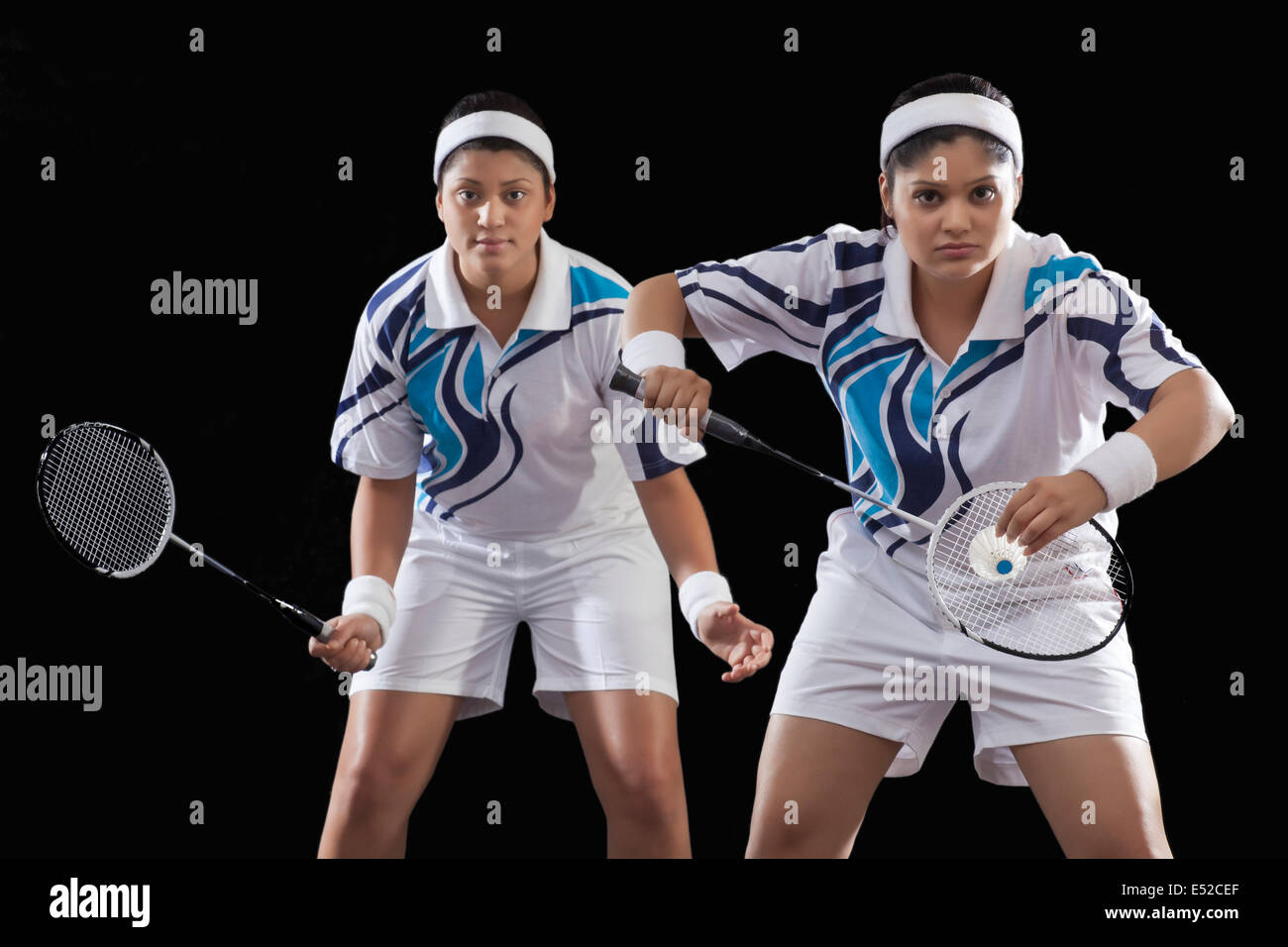 Portrait of Indian female partners playing badminton isolated over ...