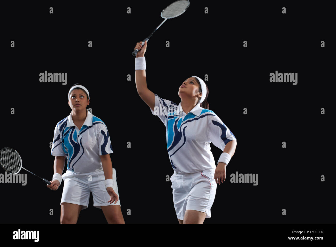 Young female partners in sportswear playing badminton against black ...