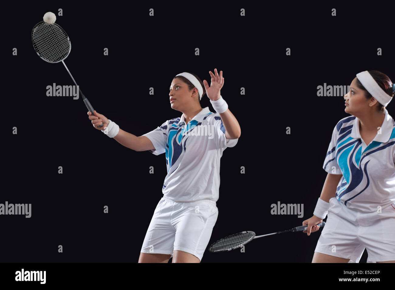 Young female player looking at partner hitting shuttlecock with racket ...