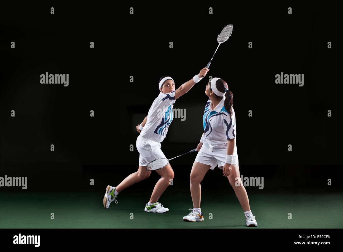 Woman looking at partner holding badminton over black background Stock ...