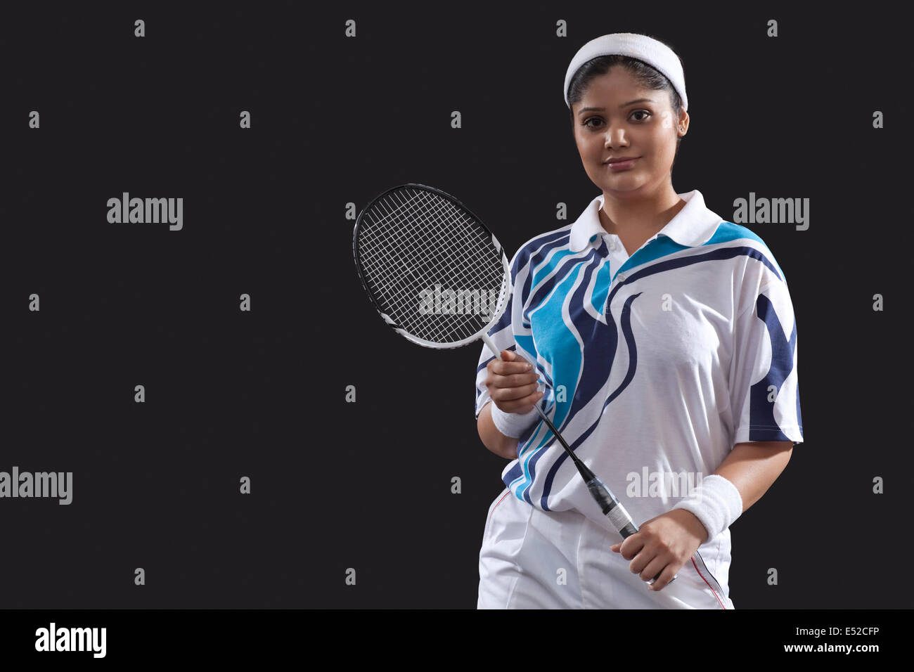 Portrait of young female player holding badminton racket isolated over ...