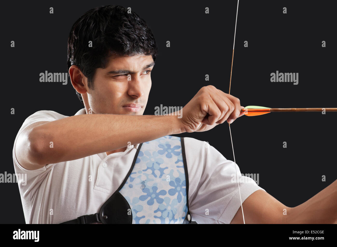 Close-up of young man aiming bow and arrow isolated over black ...