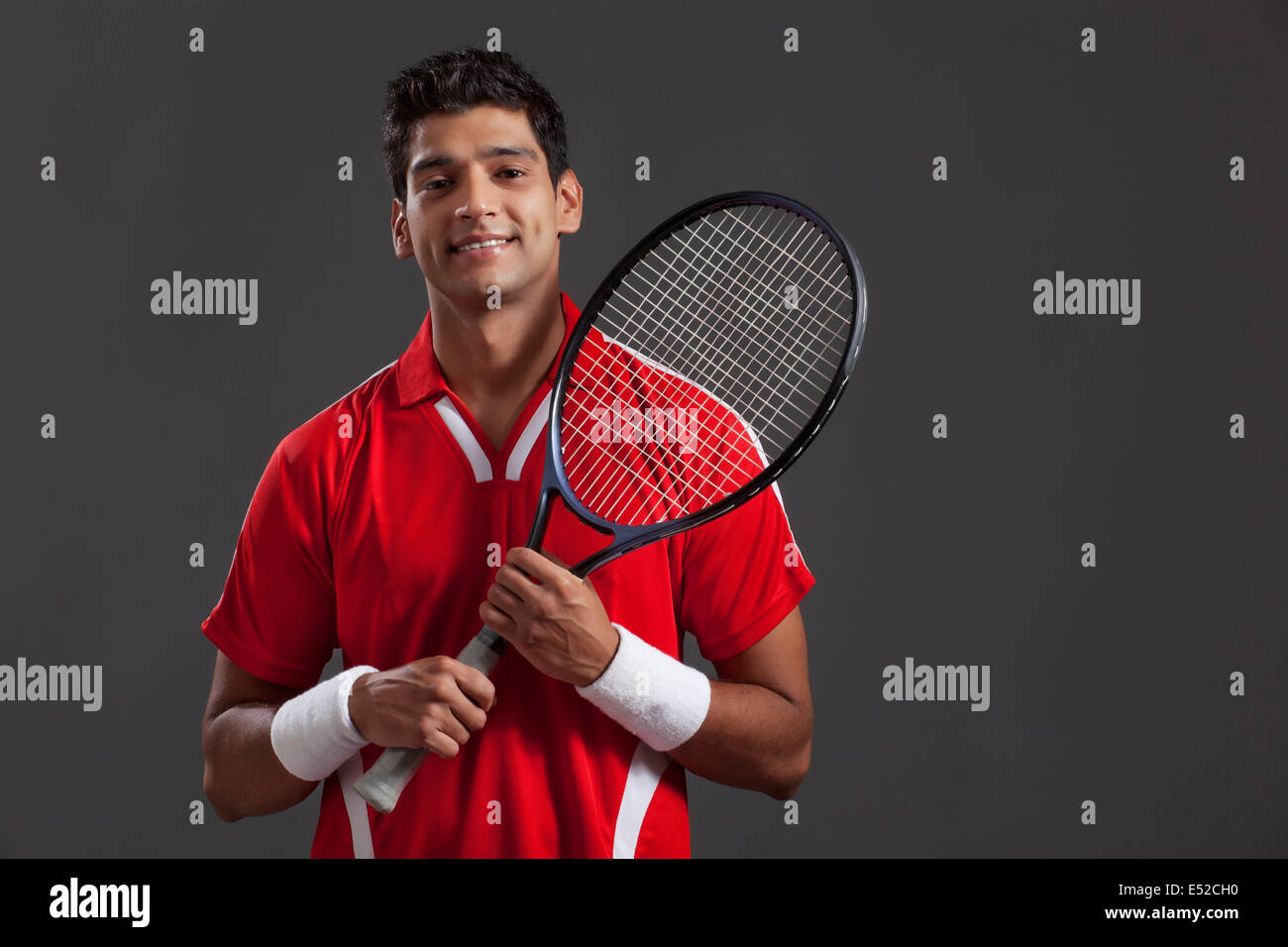 Confident young man with tennis racket over black background Stock ...