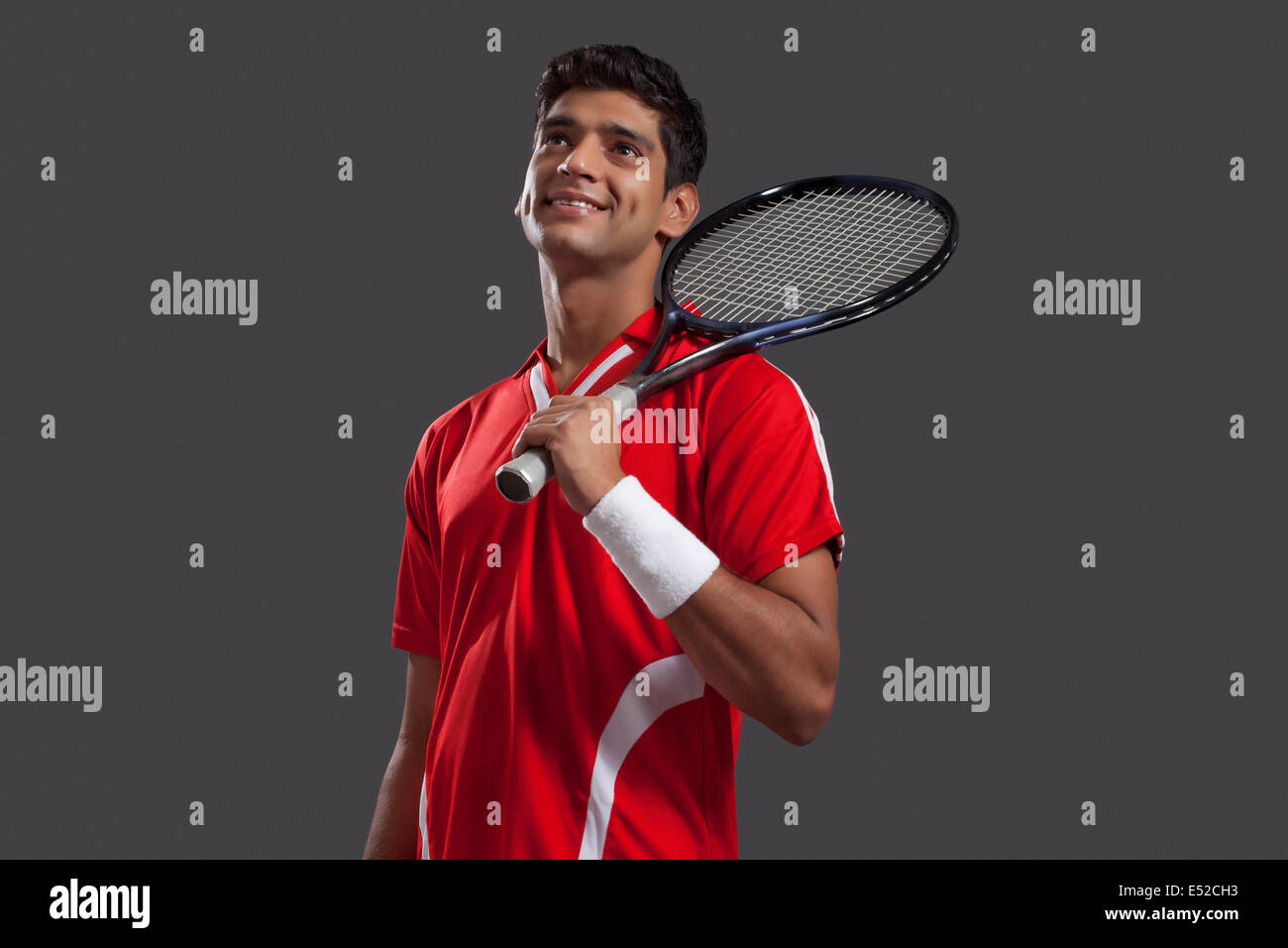 Thoughtful young man holding tennis racket isolated over black ...