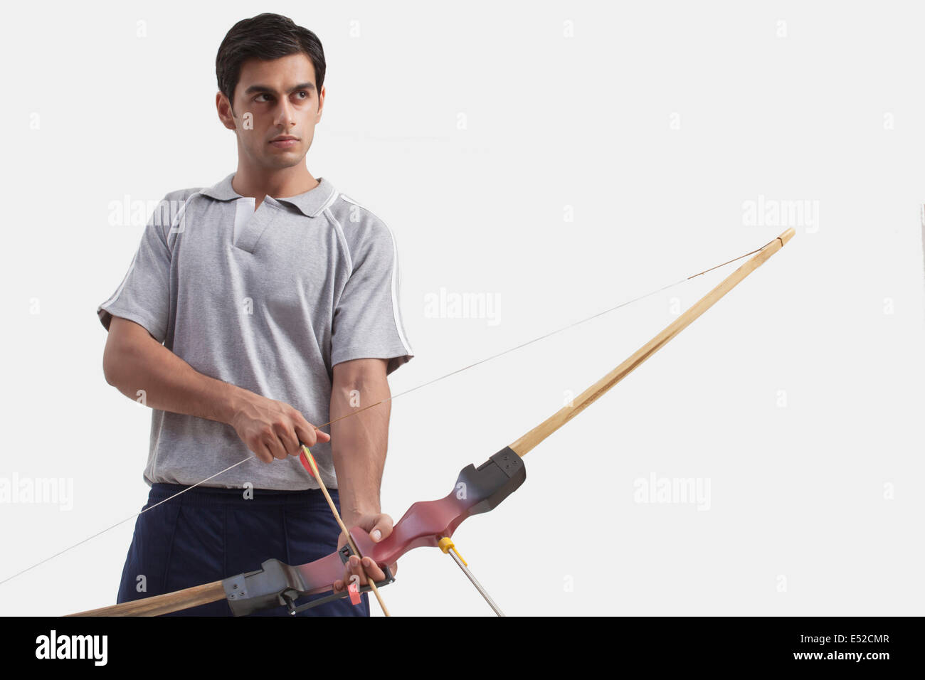 Young male archer with bow and arrow against gray background Stock ...