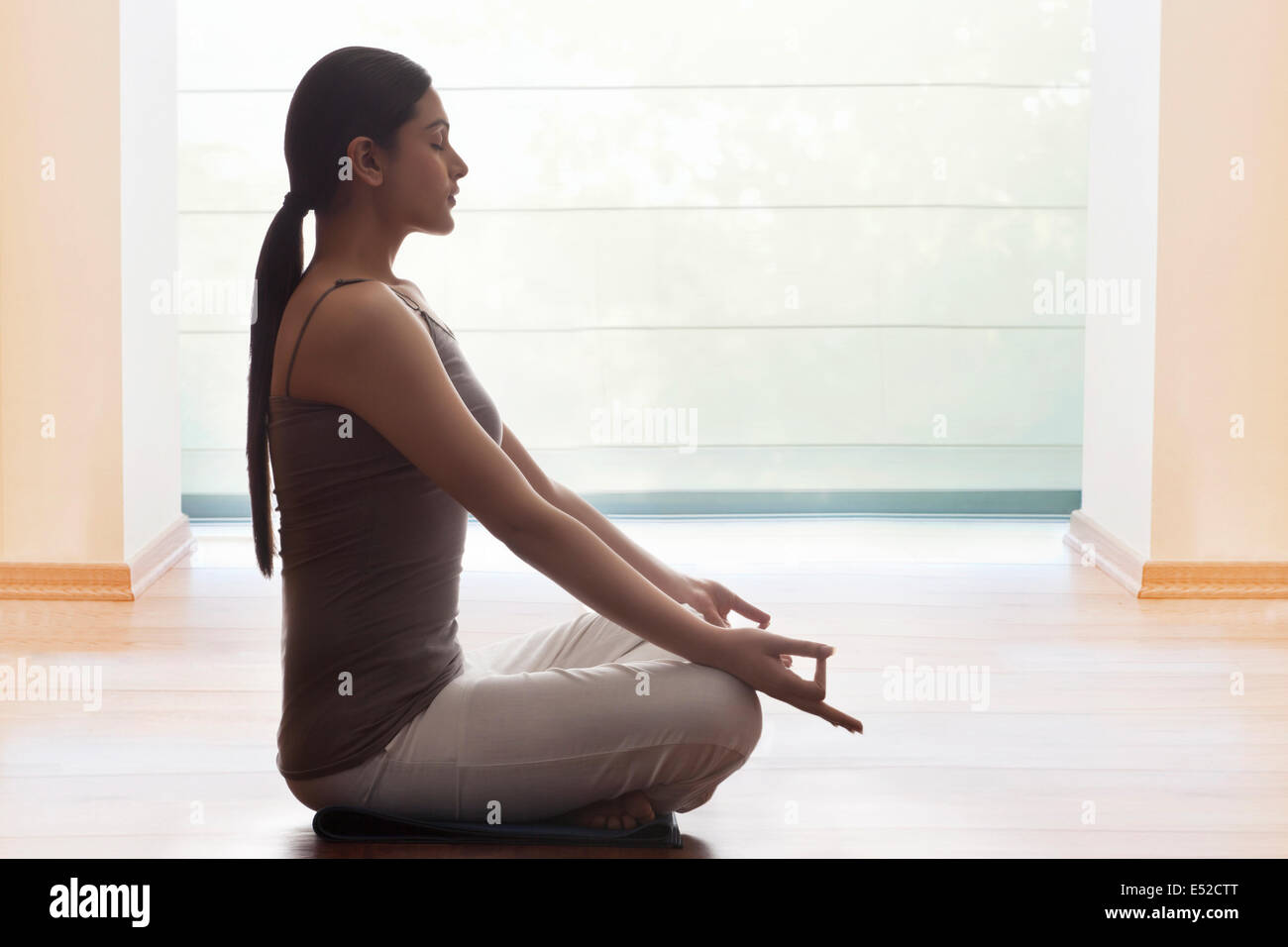Side view of young woman meditating on floor Stock Photo - Alamy