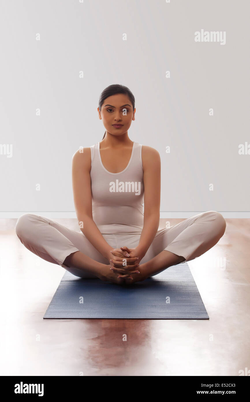 Portrait of young woman sitting in butterfly position on mat Stock ...